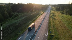 Heavy semi-trailer truck drives through beautiful terrain through the summer woods at dawn. Concept of freight, freight delivery, international trade, freight.