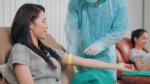 Doctor fumble blood vessel on arm of donor Asian woman preparing steps during venipuncture to blood donation at blood bank
