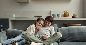 Siblings have fun laugh watch funny videos on cellphone, look at screen use cool photo editing app. Gen Alpha, Z use modern tech, smartphone overuse and addiction, parental control application concept