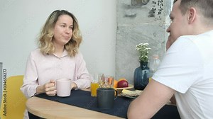 Couple eating breakfast early in the morning in the kitchen and having a good time.