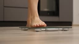 Woman legs checking weight. Female barefoot on scales measuring...