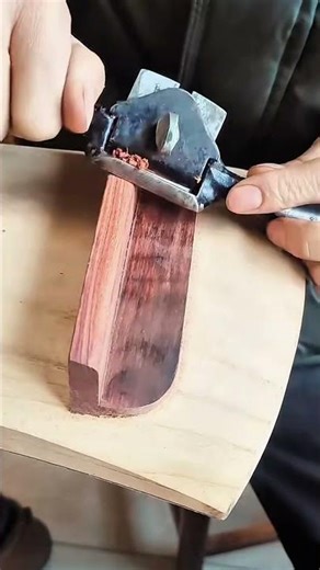 Using a hand plane to smooth and shape the surface of a curved wooden piece for fine woodworking