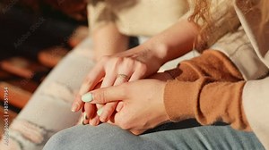 Caring young woman holding hand supporting her friend and give empathy and support. Close up of female hands of two friends girls sitting outdoors.