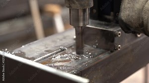 Drilling holes in iron profile with industrial machine. The technician drills a hole in the machine into an iron profile.