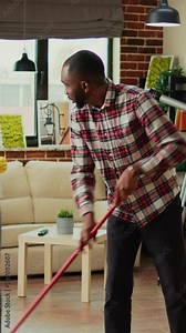 Vertical video: Diverse people vacuuming floors and cleaning furniture on shelves, sweeping mess or dirt with tools. Man and woman using vacuum cleaner with suction, gloves and rags to clean household