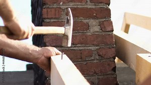 construction roofer carpenter worker nailing wood board with hammer on roof installation work