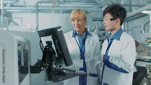 On High Tech Factory Asian Engineer Talks with Female Supervisor, Use Computer for Programing Pick and Place Electronic Machinery for Printed Circuit Board Surface Mount Assembly Line