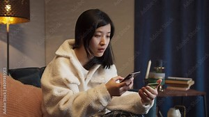 Chinese asian woman at living room christmas online shopping. female booking hotel and order on phone presents using credit bank card home during coronavirus lockdown. Food and restaurant delivery