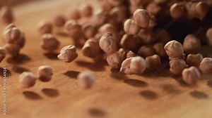 Chickpea grains pass in front of the camera in slow motion on a wooden floor. Very Close-up, 900 fps video.Macro,Phantom Camera.