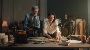 Mature tailor shows sketch of future clothes collection to seamstress on digital tablet computer. They choosing patterns for tailoring in luxury atelier. Concept of fashion, style and hand craft.