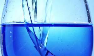 Abstract blue water splash in a transparent glass, droplets cascading down the rim