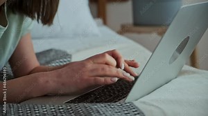 Close up woman hand using laptop, typing, using touchpad, lying on the bed, remote work, work at home