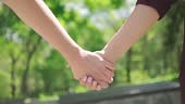 Close-up female couple holding hands, lesbians hands joining together...