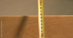 Measuring the size of the wooden board with a tape measure in centimeters seen from above 4k video