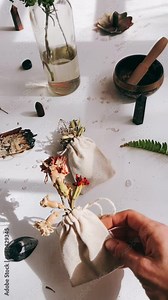 woman setting two pouches full of flower on table, woman setting table for arts and crafts, arts and crafts, dried flowers, still life flowers, a table setting