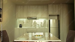 Silhouette of couple of people reflected on tile in modern small kitchen. Table, two chairs is morning breakfast a cup of coffee, sweet bun on plate.Modern kitchen in hotel condo apartments flat home