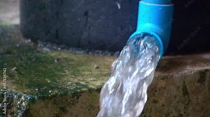 PVC Pipe with Flowing Water from a Filtration System for Waste Runoff. Blue Drainage Pipe Outside with Rainwater Overflow from Guttering. Water Supply Leakage Flowing in Slow Motion.