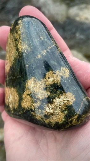 StoneBorn Creations on Instagram: "I picked up this stone in the river this weekend thinking it was nothing special. Just another dark, dull rock covered in mud… the kind most people walk right past. But something told me to polish it right there on the riverbank. And when the mud came off, THIS showed up — deep glossy green with those wild gold/tan patches running through it. Most likely serpentine with iron-oxide staining, maybe even a little magnetite in the darker spots. Nature hides beauty 