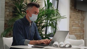 Mature business man wears face mask and works with a laptop inside the office. copy space. Free Stock Video Footage