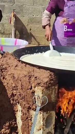 A food dough that is being cooked by a woman using a large container