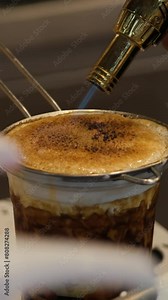 Vertical video. Close-up of bartender melting grated chocolate with Gas burner on iced coffee cocktail