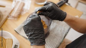 Adding Cookies to the Food Processor, the Process Continues with Precision. Black Gloves Emphasize Cleanliness and Attention to Detail in Baking.