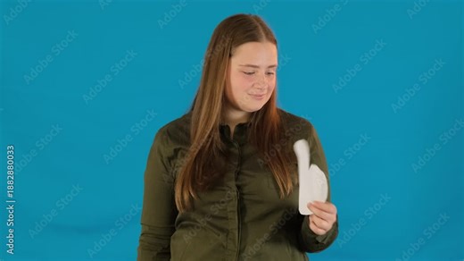Cheerful female student clutches paper heart-shaped decoration in hand. Young woman assists adorning classroom for party slow motion