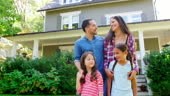 Portrait Of Smiling Family Standing In Front Of Their Home