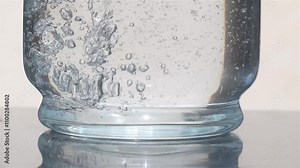Bubbles rising in slow motion inside a clear glass jar revealed in stunning detail