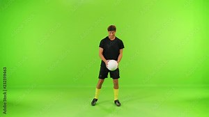 Soccer player does a Neck Stall, winks and play with a ball, slow motion over a green screen, high speed shutter, slow motion, 2 takes.