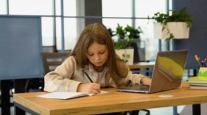 Pupil girl doing her homework using laptop in primary school. Child using technology on elementary computer science class