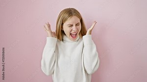 Excited blonde girl gone mad with victory, standing over pink isolated background, celebrating her crazy win with arms raised. beautiful success is a true winner's face!