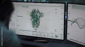 A patient in the background. CT scan. The doctor is sitting by the two computer screens. Supervising the deep virus analysis process. SARS-COV-2 Spike Protein Structure was identified. User Interface.