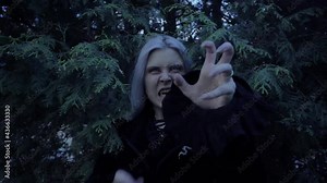 Terrible werewolf woman with large fangs at night. She stretches out her arms to grab.