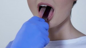 General practitioner checking patient throat with medical tongue depressor