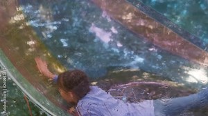 A child in a balloon on the water. A young girl in a protective helmet and insurance passes an obstacle course.