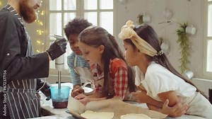 Male chef explaining how to use hand blender to group of little multiethnic kids during cooking class