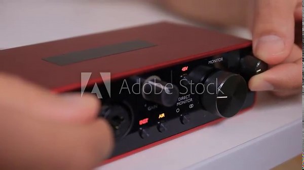 Adjusting external sound card knob, Precise control over audio output through knob rotation, Modifying sound levels using detailed textured dial on external audio interface