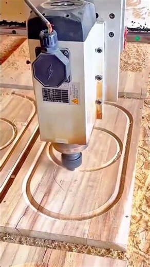 A person uses a CNC machine to carve a pattern into wood