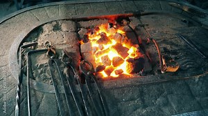 Smithing tools lying near a fire at a forge.