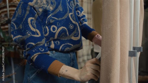 Young woman with prosthetic arm carefully steaming secondhand jacket, while working herr shift in modern thrift store