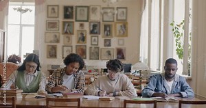 Multiracial group of students studying together then looking at camera and smiling in college classroom. Education and multiculturalism concept.