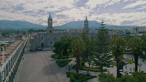 Aerial drone shots above streets and vegetation leading to Arequipa Cathedral, concluding with a view of the snow-covered Misti volcano after a rainy and cloudy day