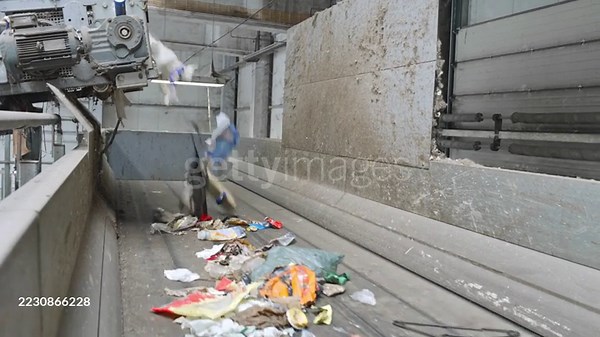 Wide shot of mixed waste falling onto a conveyor belt at a recycling...