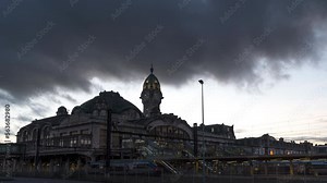 Day to Night Timelapse of Benedictin Train Station of Limoges City by winter and clear blue sky with cloud and night light, France