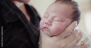 Closeup lovely little newborn baby infant girl in her mom arms being burped and patted rubbed on the back of the child to encourage burping after eating full milk at home