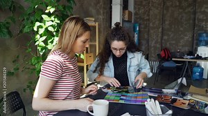Creative designers are watching professional photos and checking color palettes comparing colours and discussing them. Modern loft style office in background.