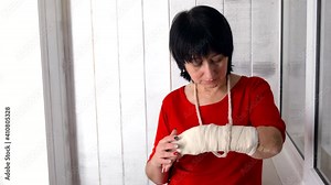a broken arm. Close-up of the plaster. A lady in a red jacket with a bright manicure. exercises to restore and strengthen the muscles. damage to the bones.