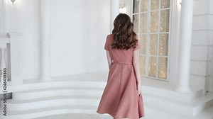 A young girl is spinning in a pink dress in a white room on the background of a ladder and a high window. Slow Motion 1920x1080