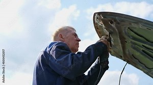 Car body shop. Repair man processes the welding seam using an angle grinder on replaced car part. Professional Body master grind old paint and rust. Rust damage. Rusting car. Hands with tool close-up